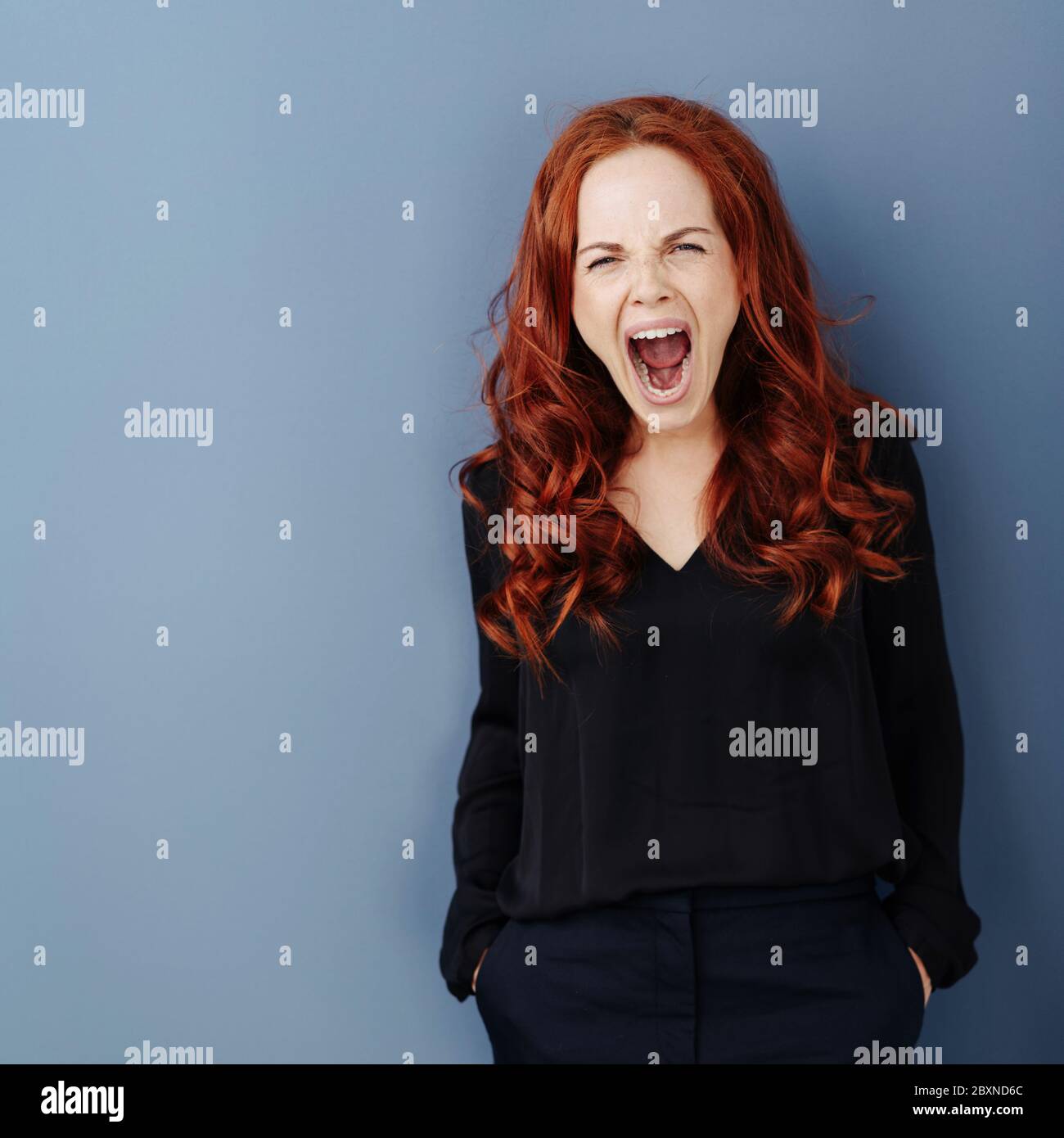 Angry young woman screaming with rage as she glares balefully at the ...