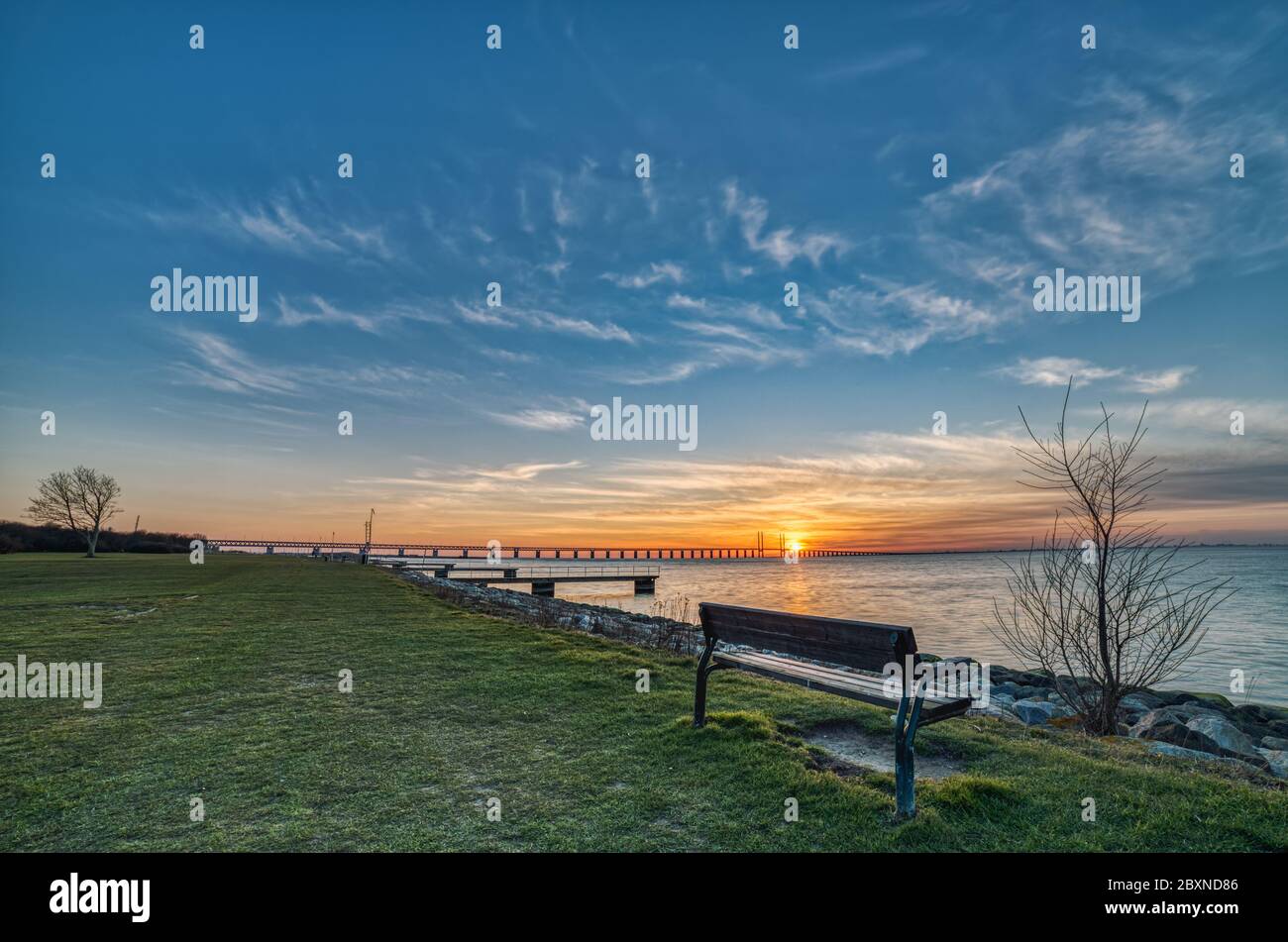 Wooden bench outdoor facing the Oresund Strait with a tranquil sunset ...