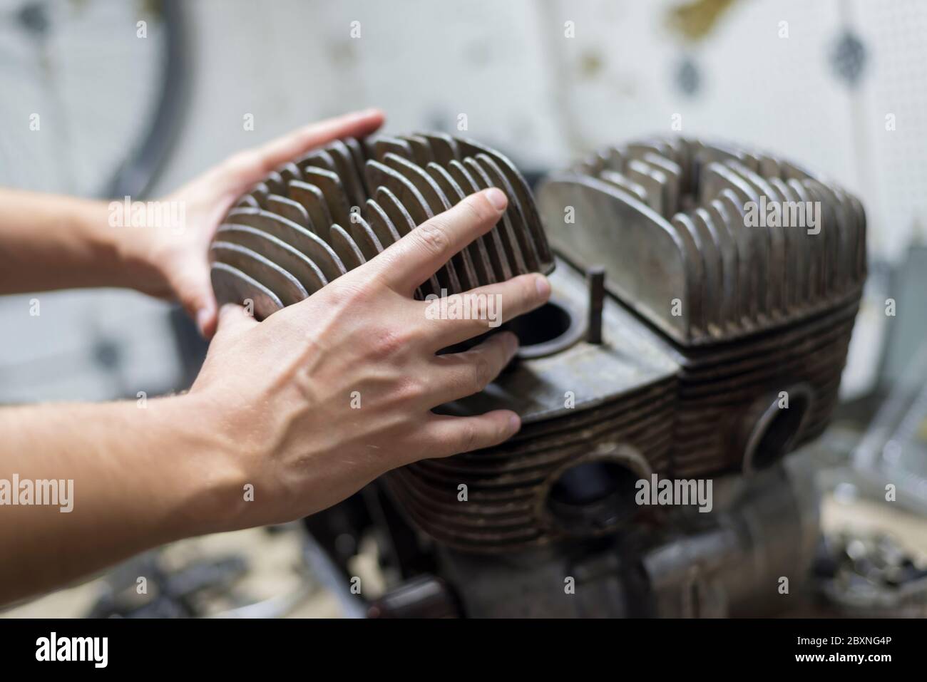 A man fixing a motorcycle motor in a garage,hands holding a cylinder ...