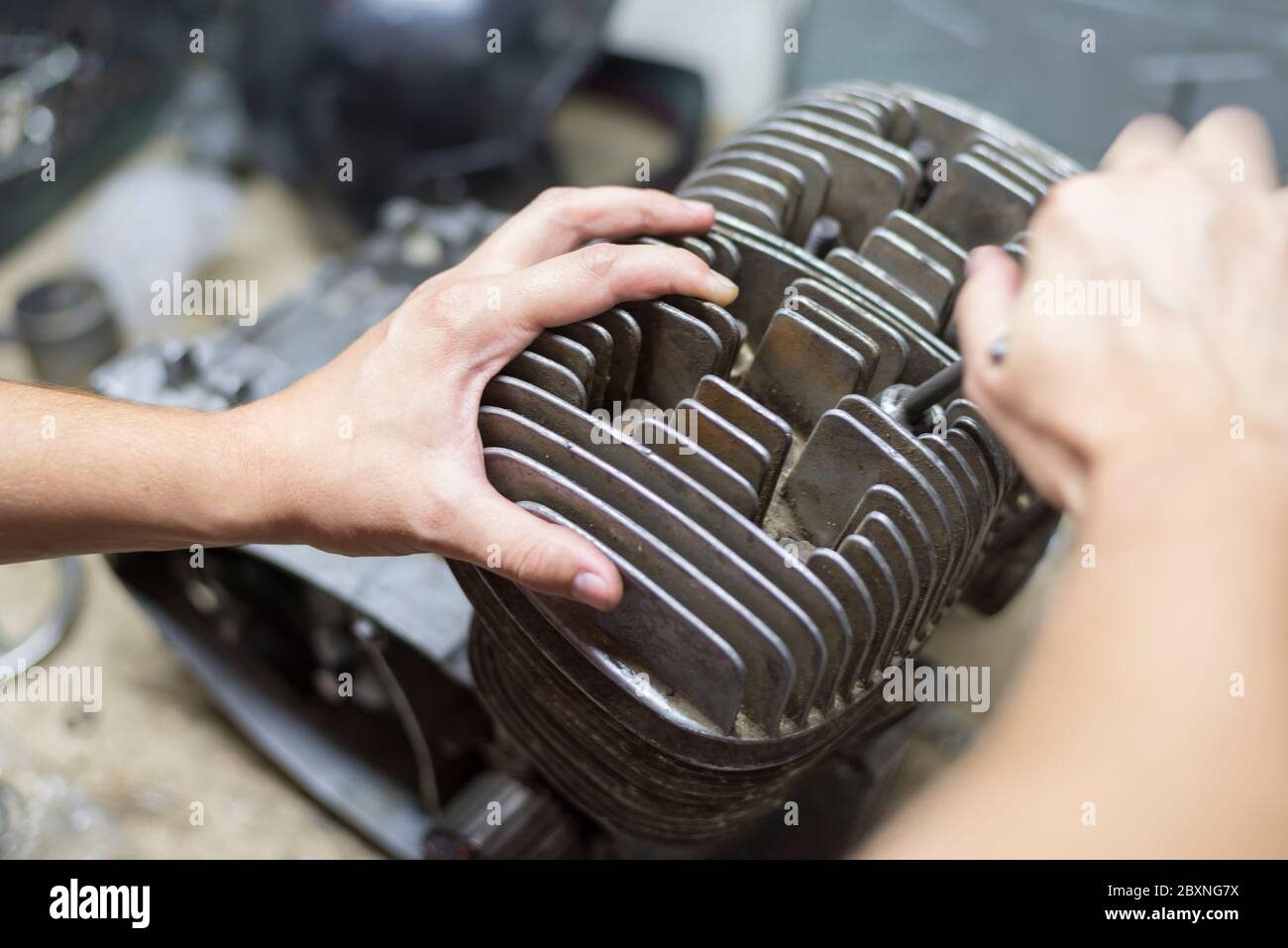 A man fixing a motorcycle motor in a garage,hands holding a cylinder ...