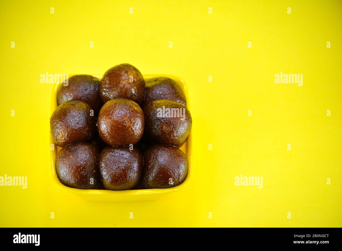 Indian dessert gulab jamun served in yellow bowl Stock Photo - Alamy