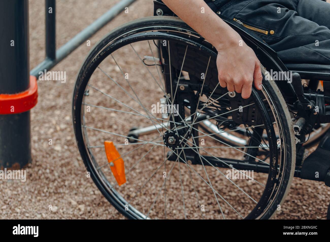 Close-up of male hand on wheel of wheelchair during walk in park. He ...