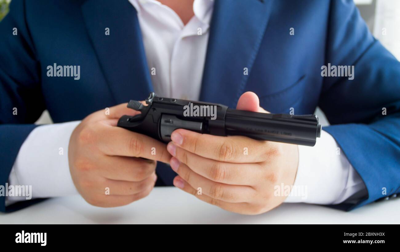 Closeup image of businessman holding gun while sitting in office Stock ...