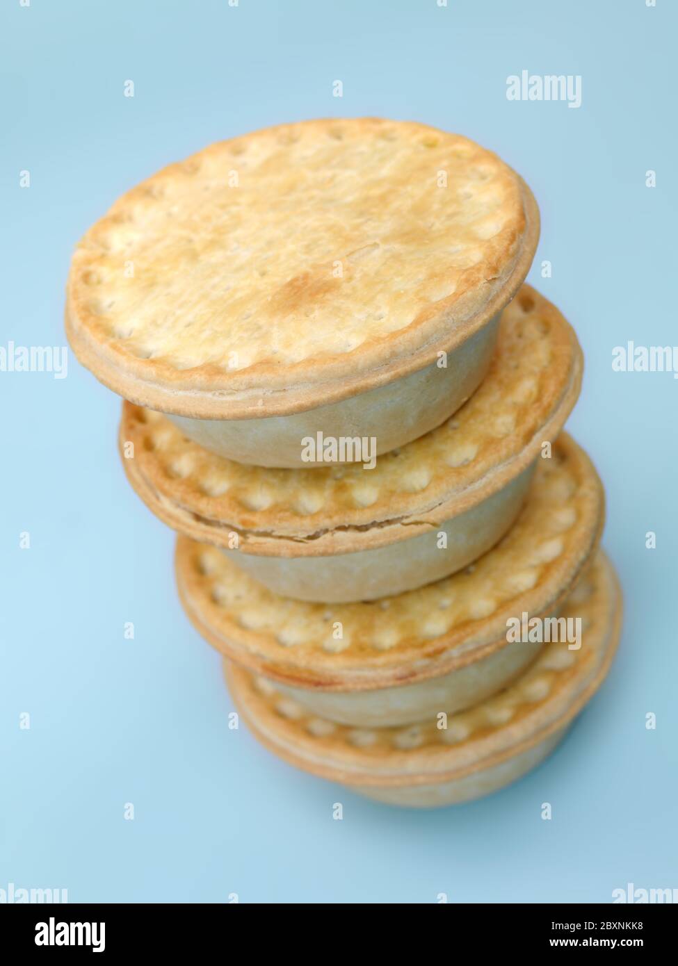 A stack of Australian meat pies isolated against a blue background ...