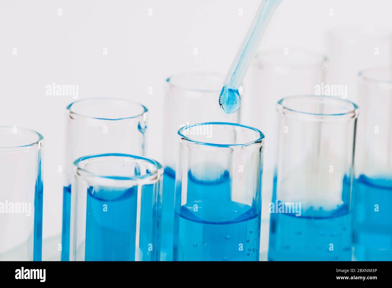Laboratory glassware with a dropper dripping liquid into a test tube ...