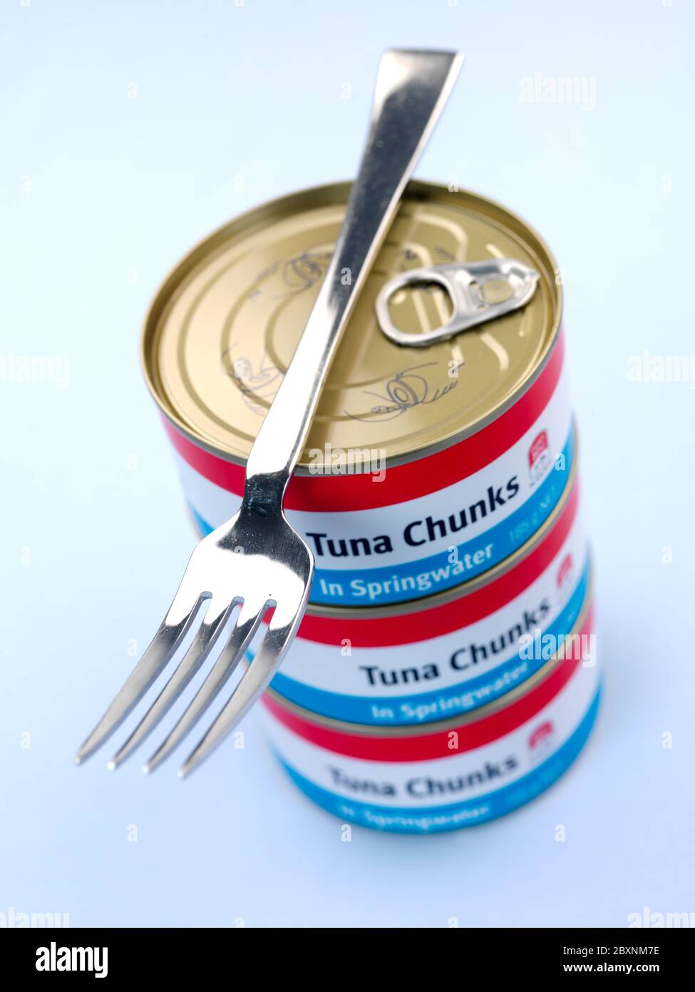 Cans of Tuna isolated against a blue background Stock Photo - Alamy