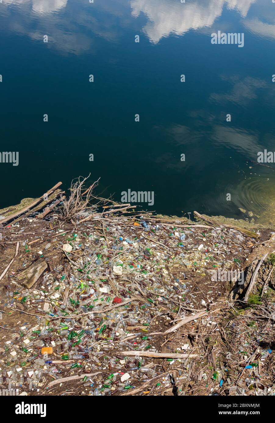 Water reservoir, polluted with plastic, reflecting the sky Stock Photo ...