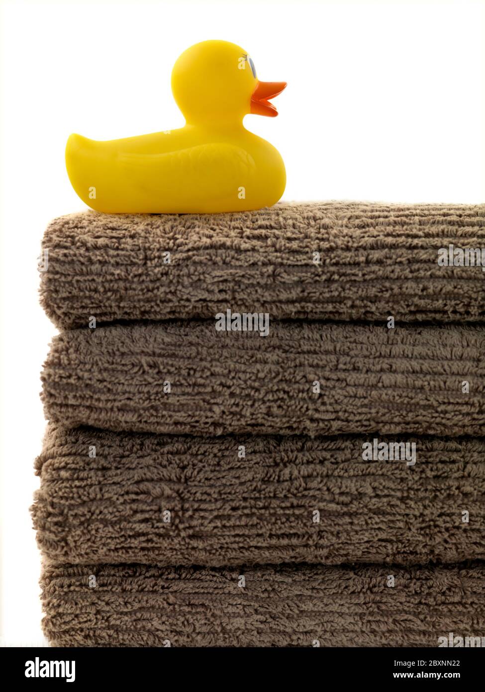 A stack of bath towels and a rubber duck isolated against a white ...