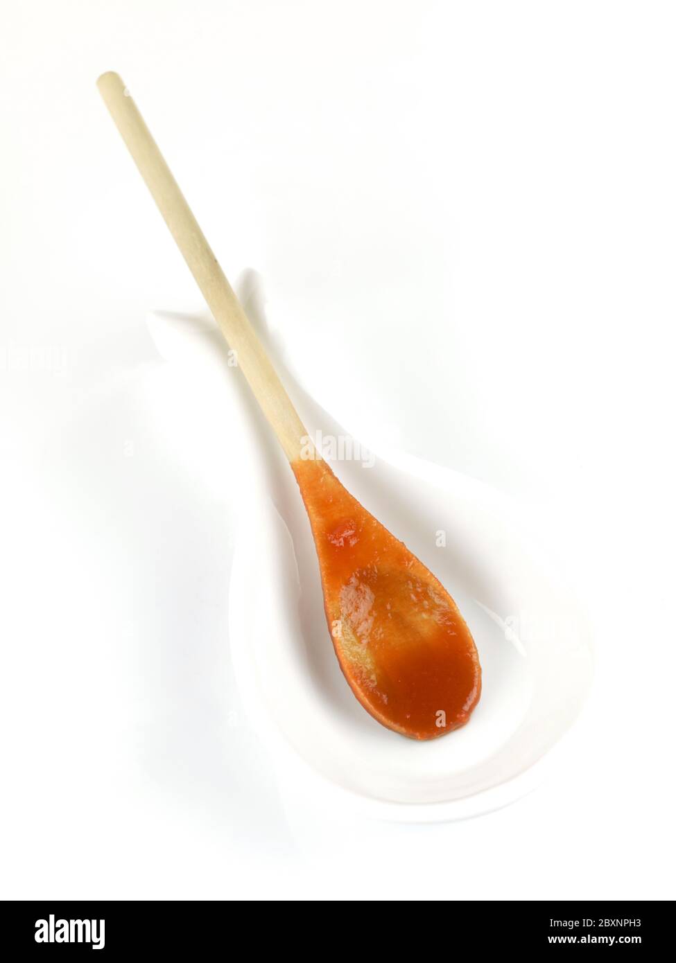 A wooden spoon covered in tomato paste isolated against a white ...