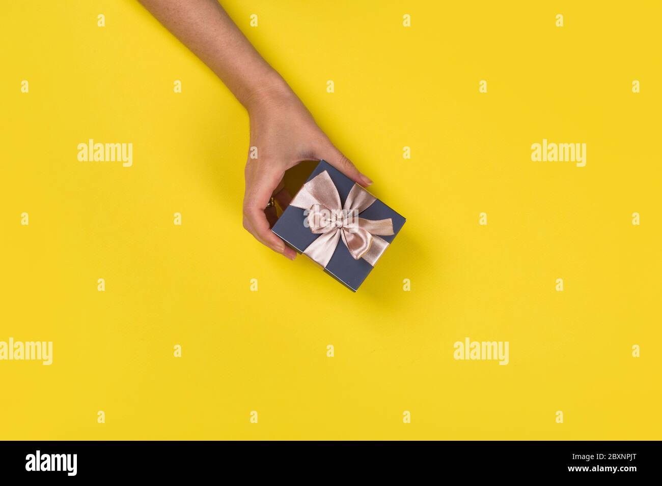 Womans hands holding gift or present box on Yellow table top view. Flat ...