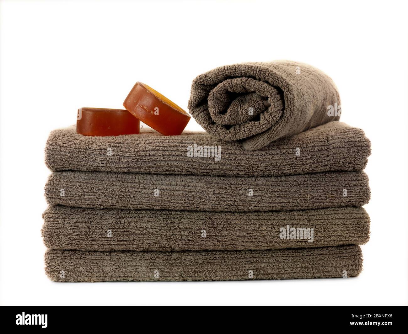 A stack of bath towels and soap isolated against a white background ...