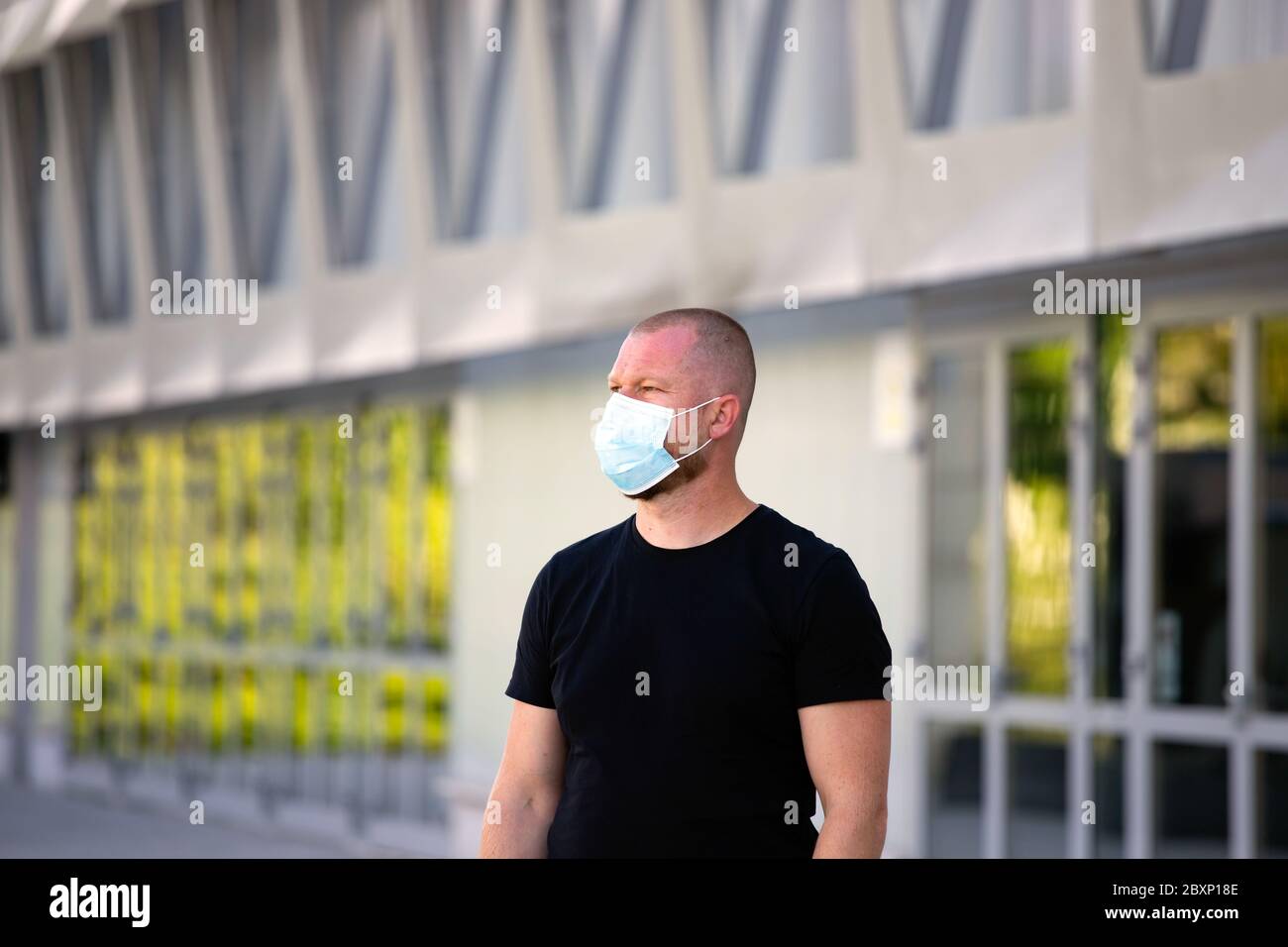COVID-19 Pandemic Coronavirus. Man in front of modern building wearing ...