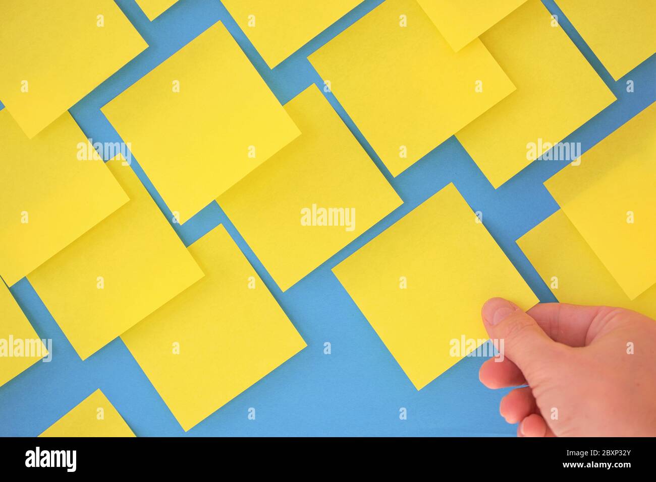 Hand holding post-it note on blue board Stock Photo - Alamy