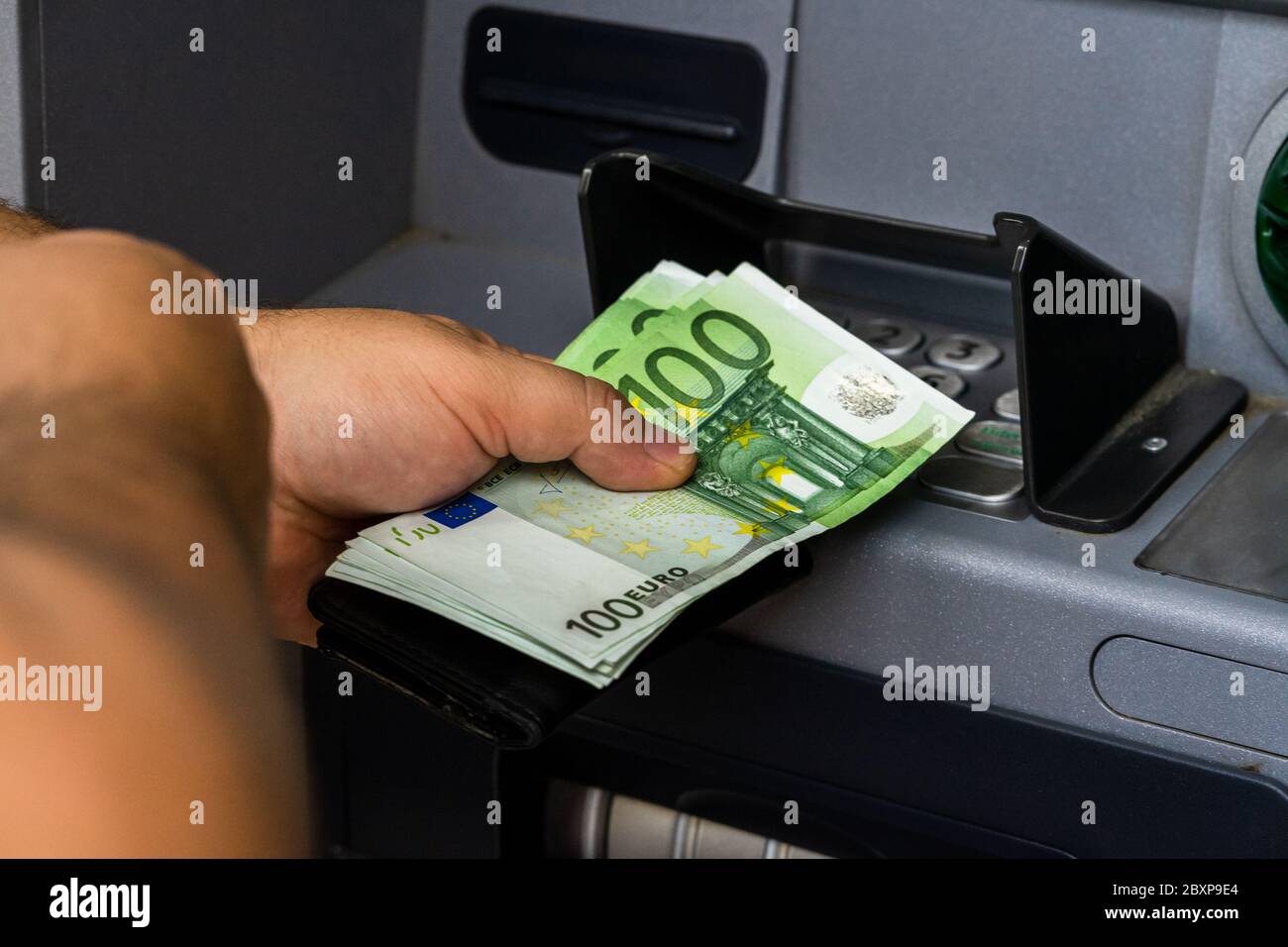 Depositor withdraws EURO from ATM cash money machine. Man hand holding ...