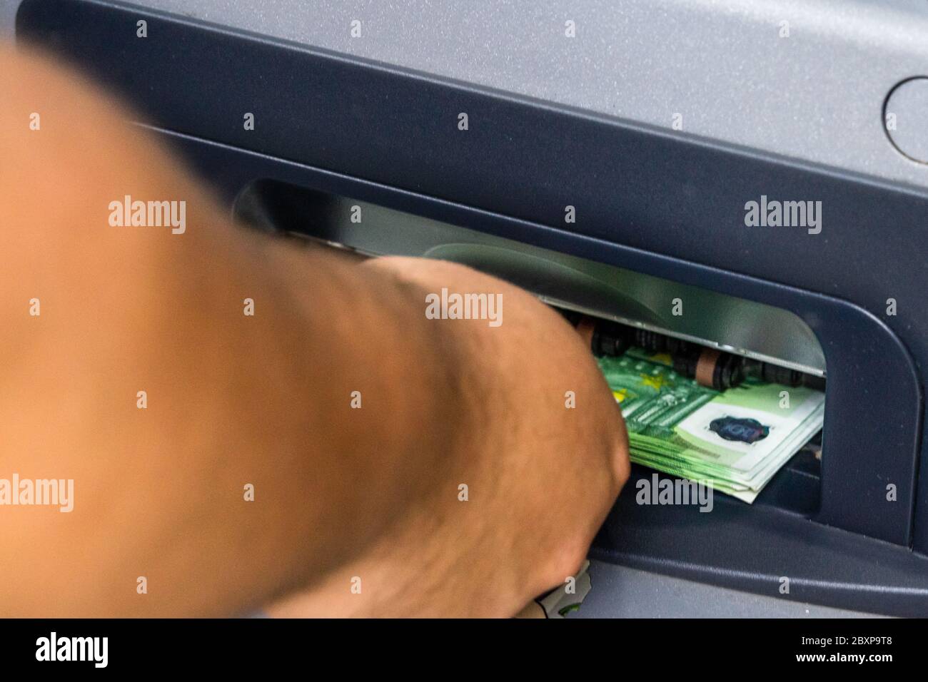 Depositor withdraws EURO from ATM cash money machine. Man hand holding ...