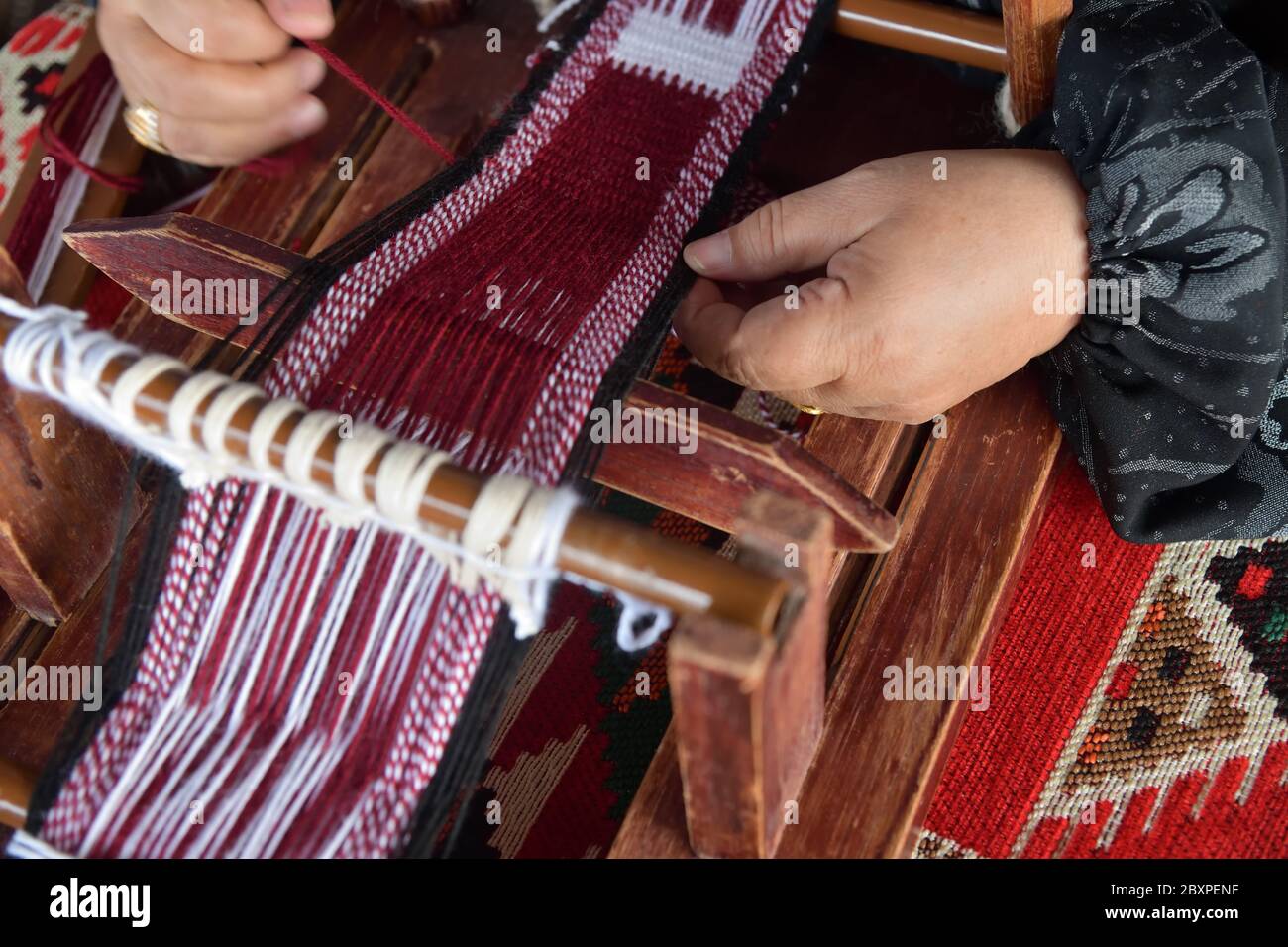 A senior arabian woman makes a traditional sadu weaving. Hands of a ...