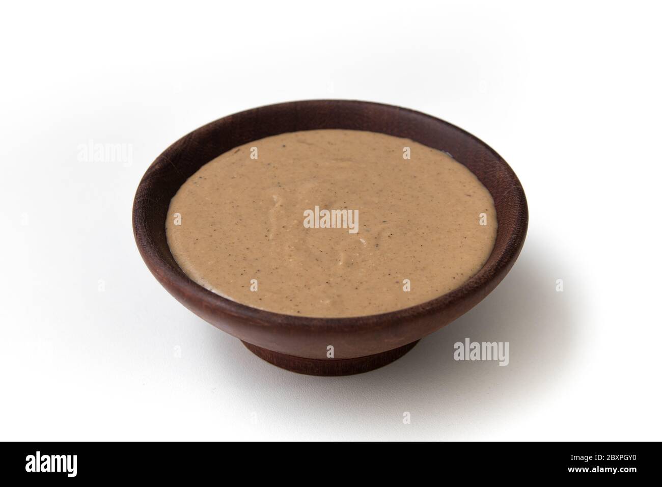 Tahini in a wooden bowl isolated on white background Stock Photo - Alamy