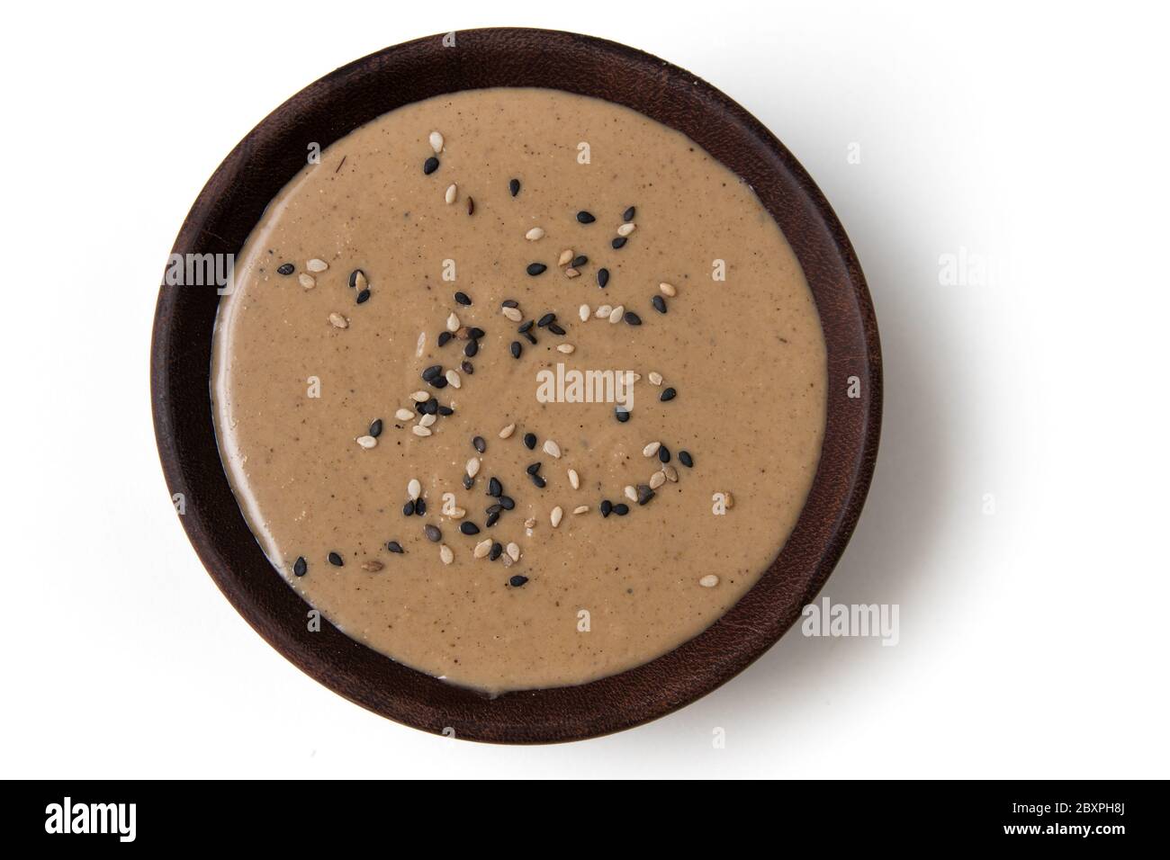 Tahini in a wooden bowl isolated on white background Stock Photo - Alamy