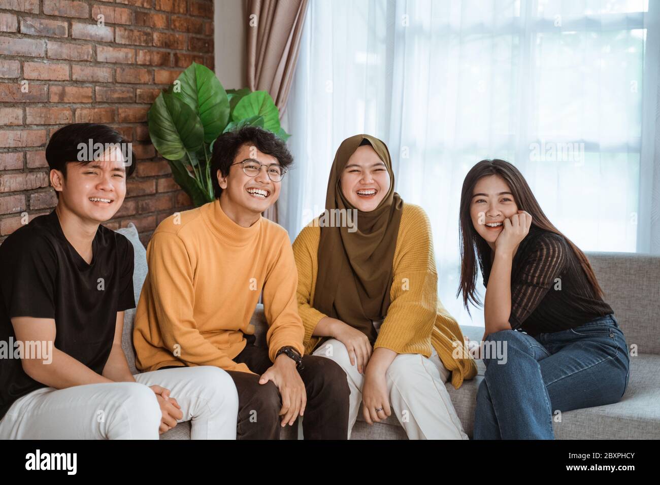 group of students sitting together on the couch laughing together while ...