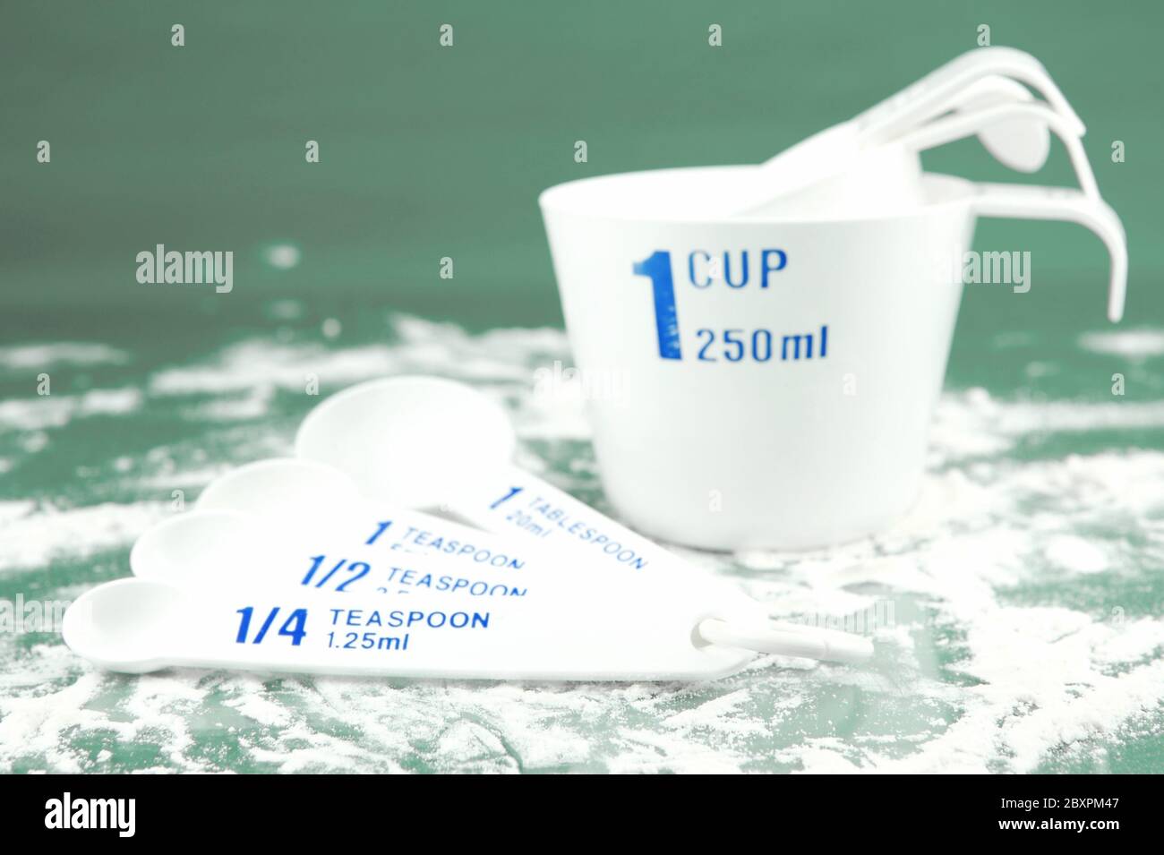 Measuring cups isolated against a green background Stock Photo - Alamy