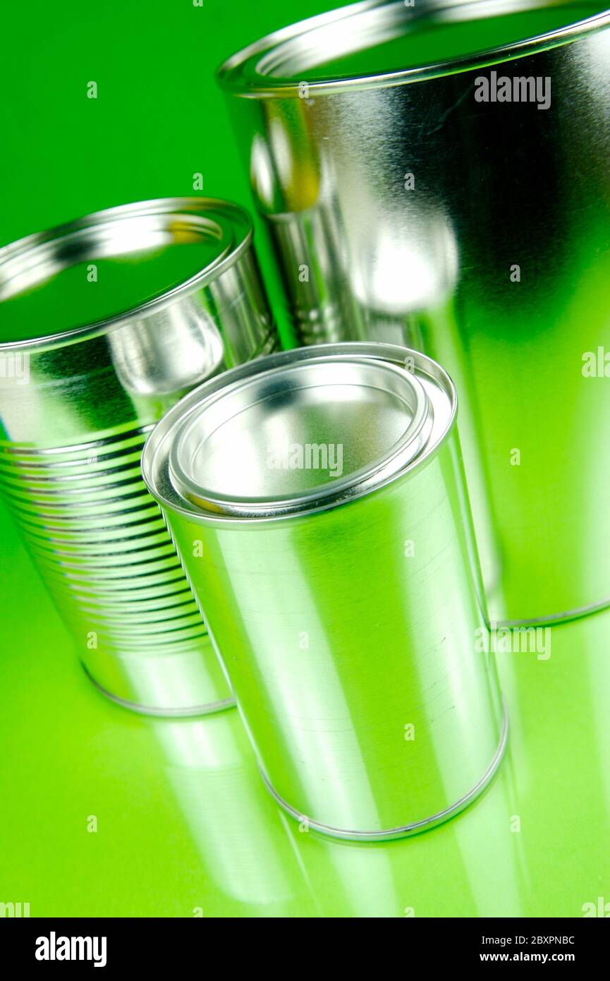 Silver tins isolated against a green background Stock Photo - Alamy