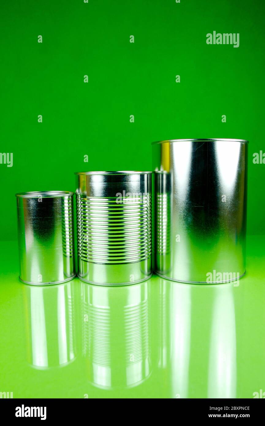 Silver tins isolated against a green background Stock Photo - Alamy