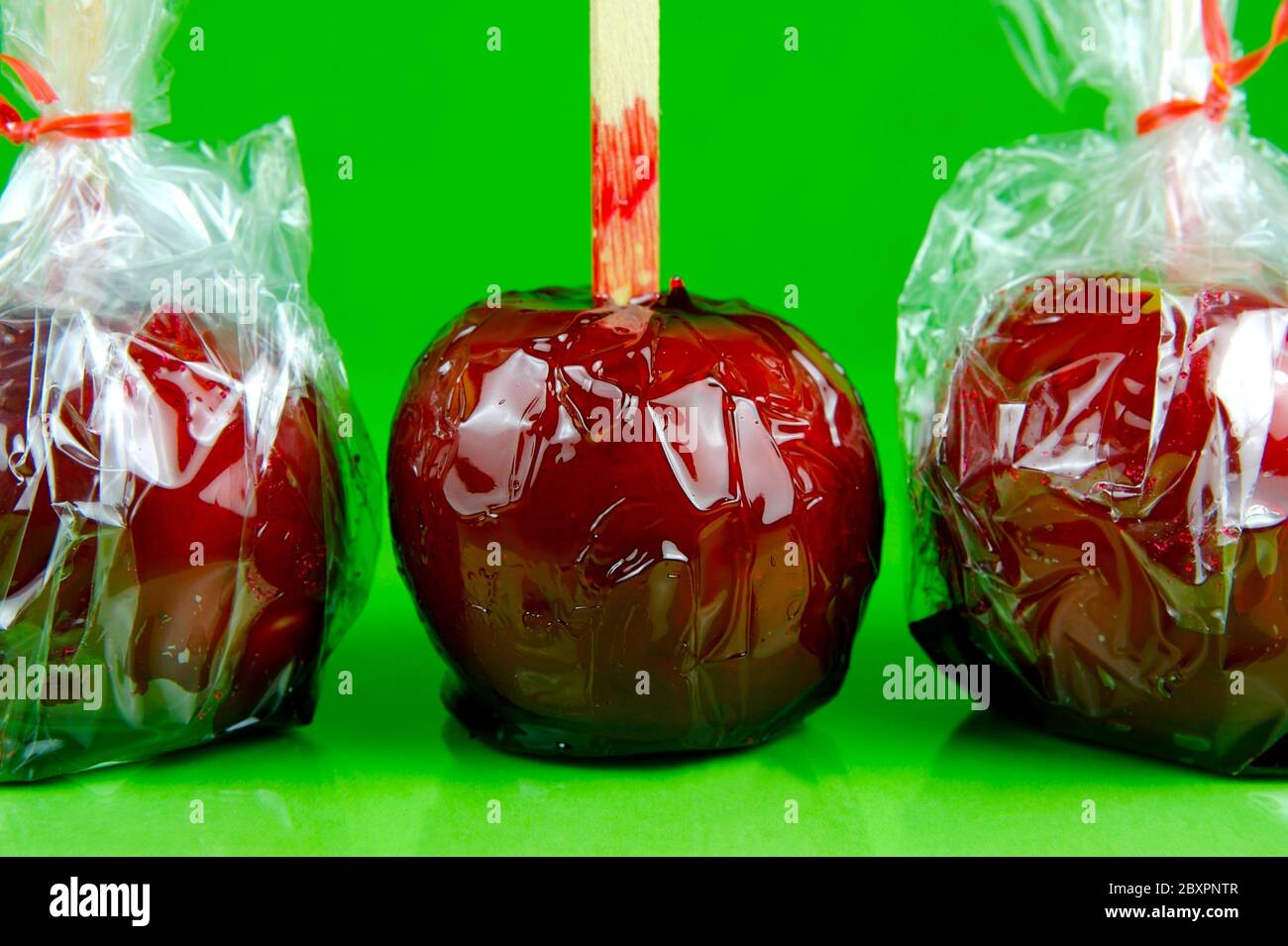 Red Candy apples isolated against a green background Stock Photo - Alamy