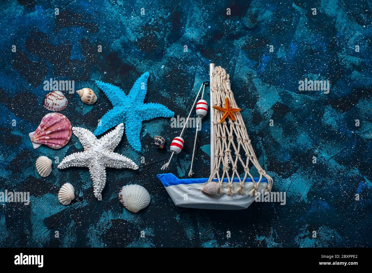 Sea composition with a boat and seashells on a dark blue background ...