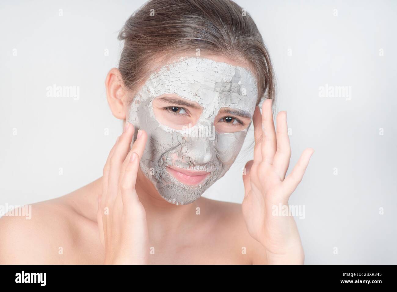 Natural Makeup Applying Grey Clay Mask On Face.Young girl in a cosmetic ...