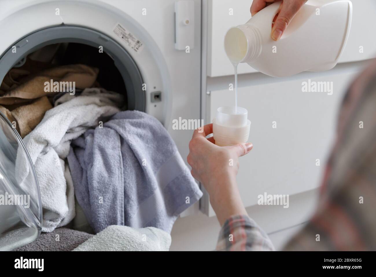 Close up of female hands pouring liquid laundry detergent into cap on ...
