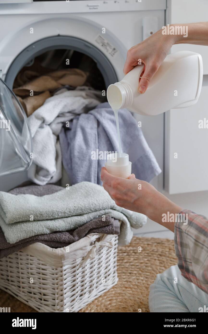 Close up of female hands pouring liquid laundry detergent into cap ...