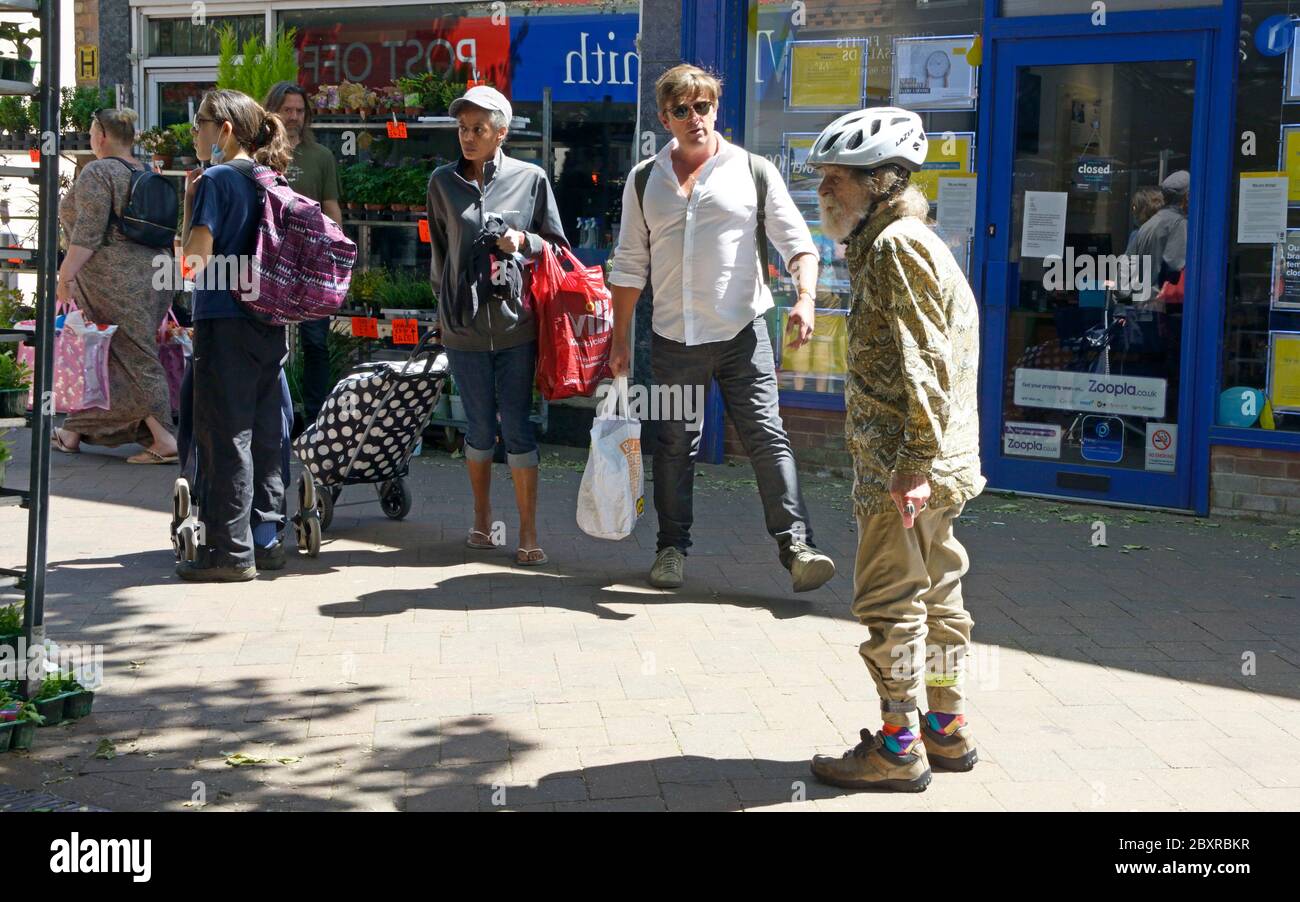 Old man in cycle helmet, in queue with others, for green grocer shop ...