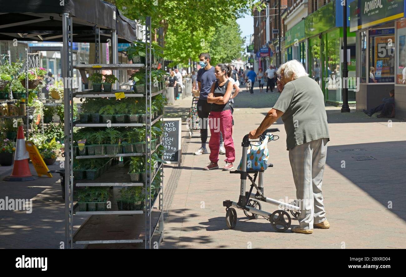 Old lady with walking frame, & queue for greengrocers shop. During ...