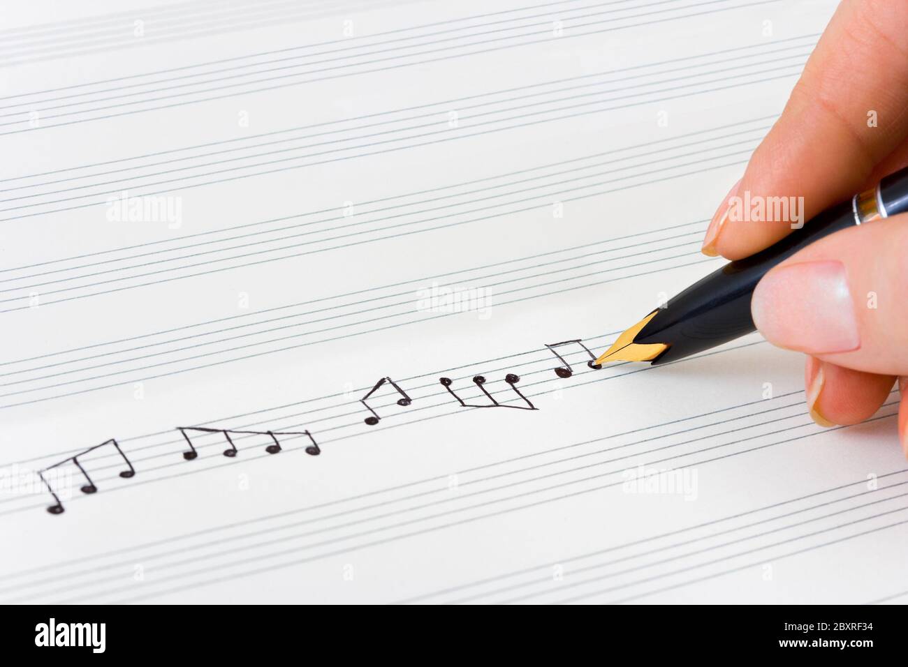 Hand with pen and music sheet Stock Photo - Alamy