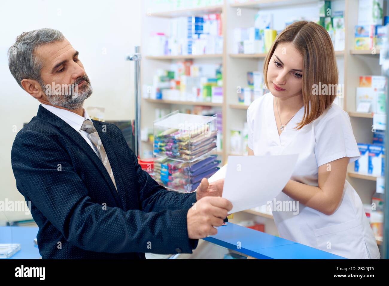 Side view of beautiful woman working in drugstore and helping ...