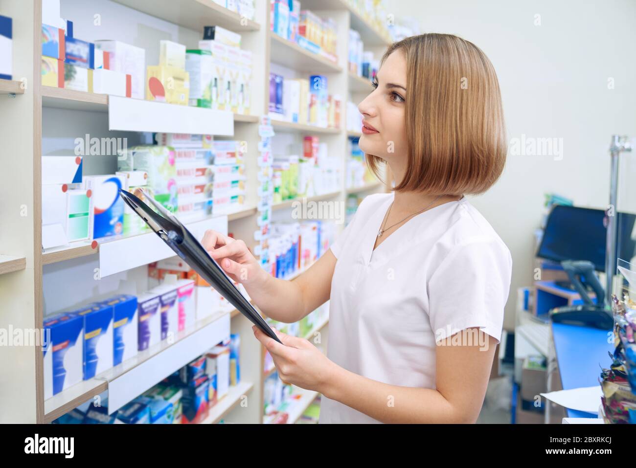 Female pharmacist standing near shelves with medicaments in drugstore ...