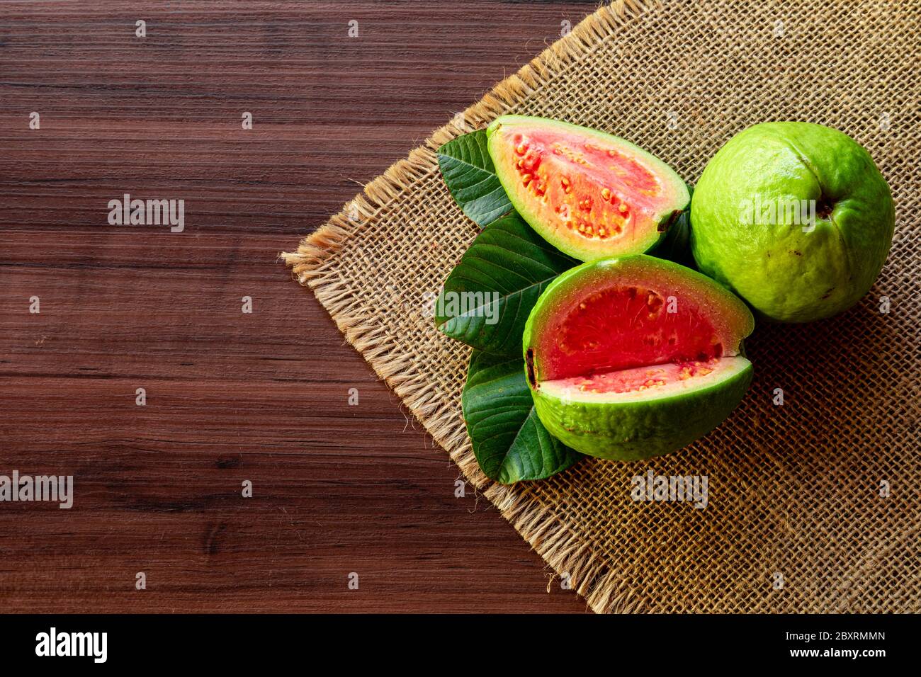 Fresh red guavas with green leaves on wooden demolition background ...