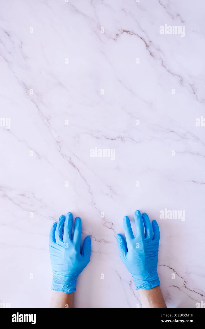 Top view of a pair of hands in medical gloves against a white marble ...