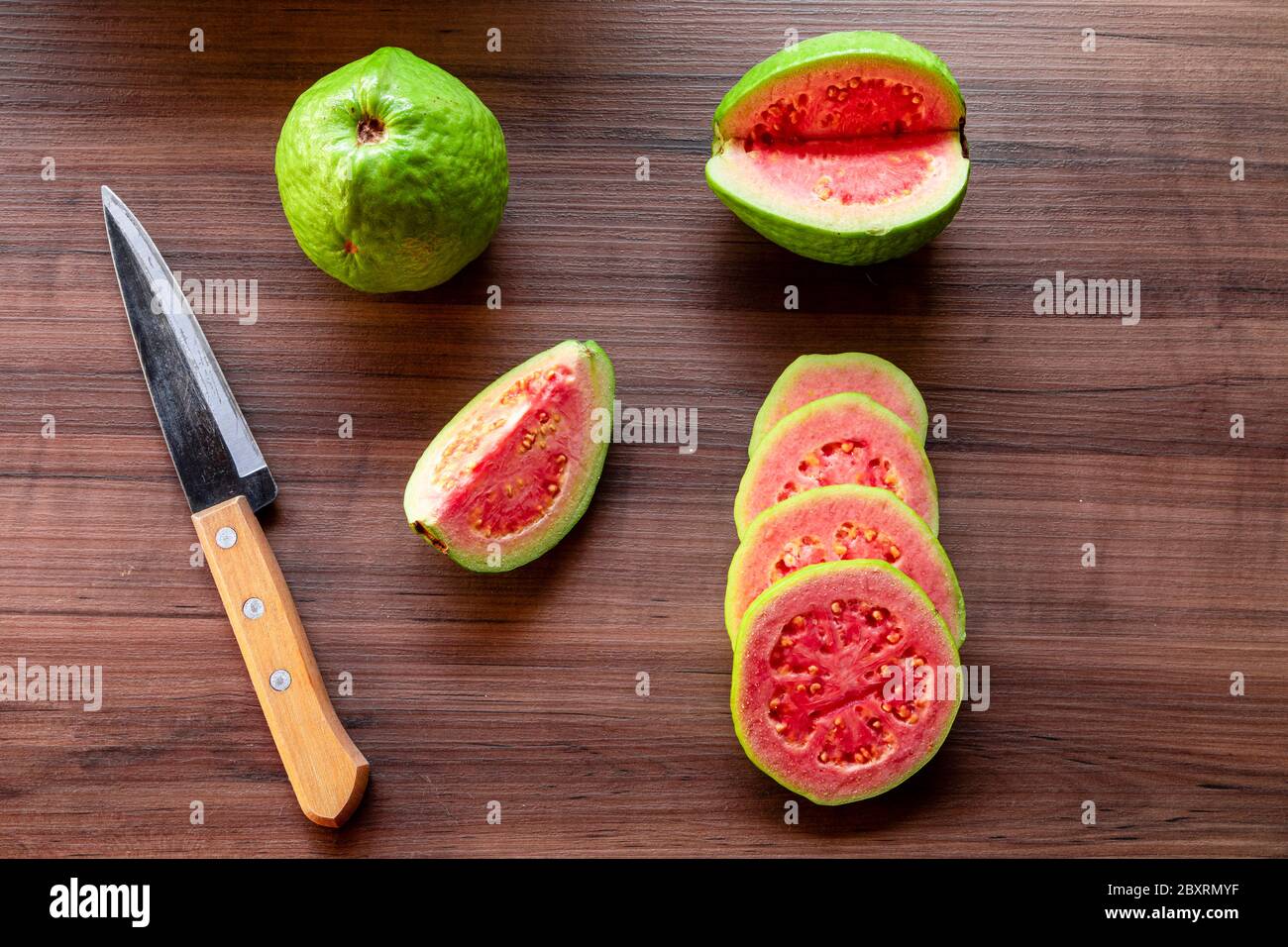 Antique steel knife and sliced red guavas on rustic wooden background ...