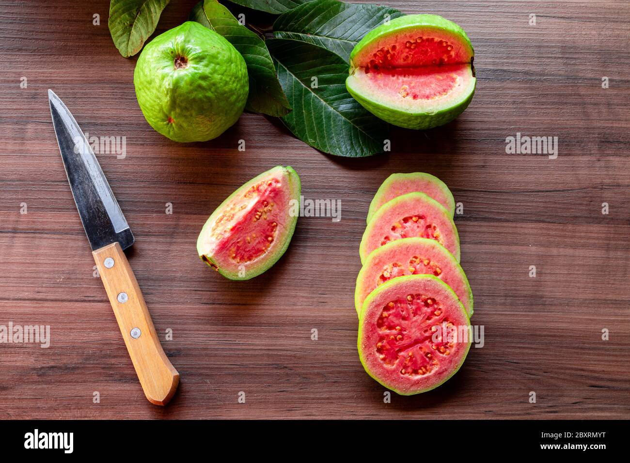 Antique steel knife and sliced red guavas on rustic wooden background ...