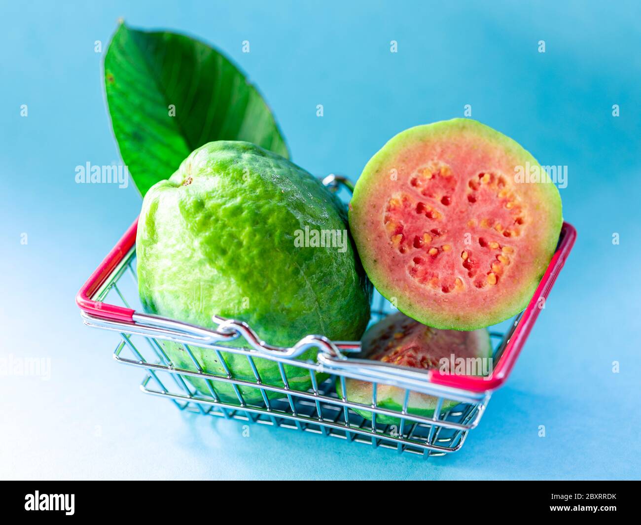 Several slices of red guava fruit in supermarket basket on blue ...