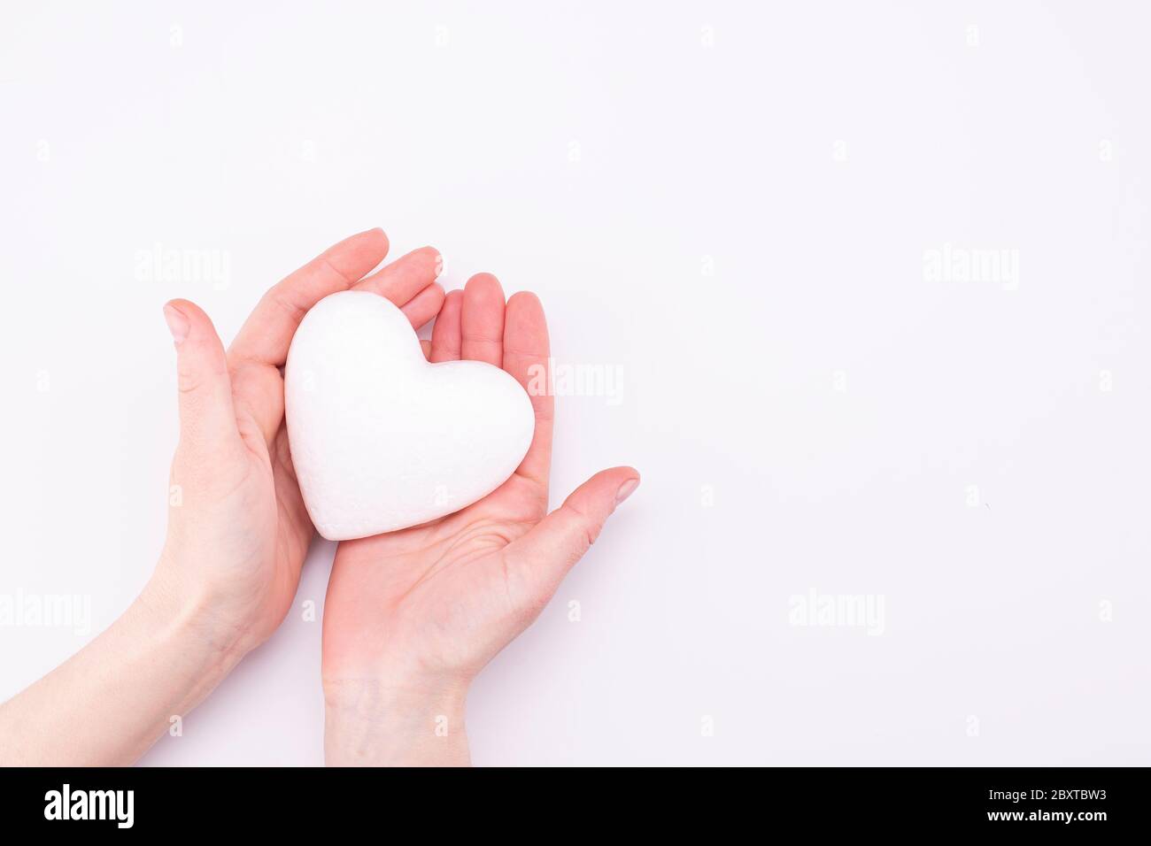 White heart in female hands isolated on white background with place for ...