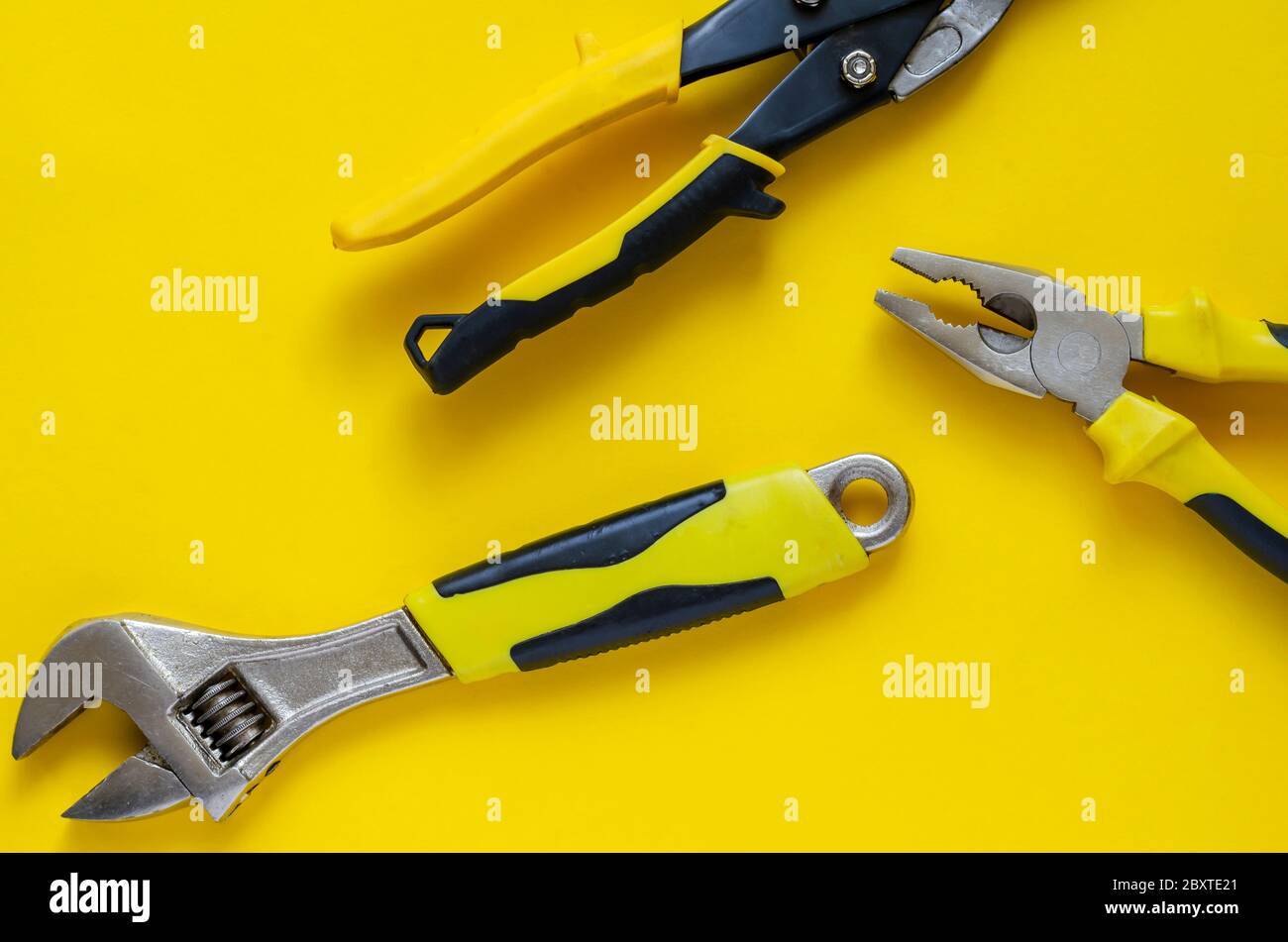 Hand tools with black and yellow handles on a yellow background ...