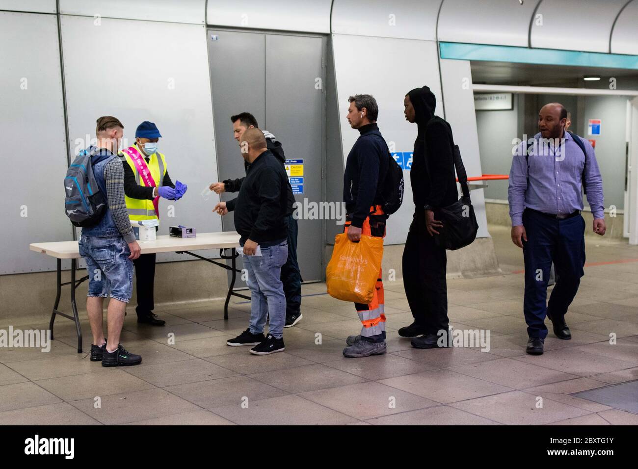 A TFL employee hands out free face masks and gloves to passengers at ...