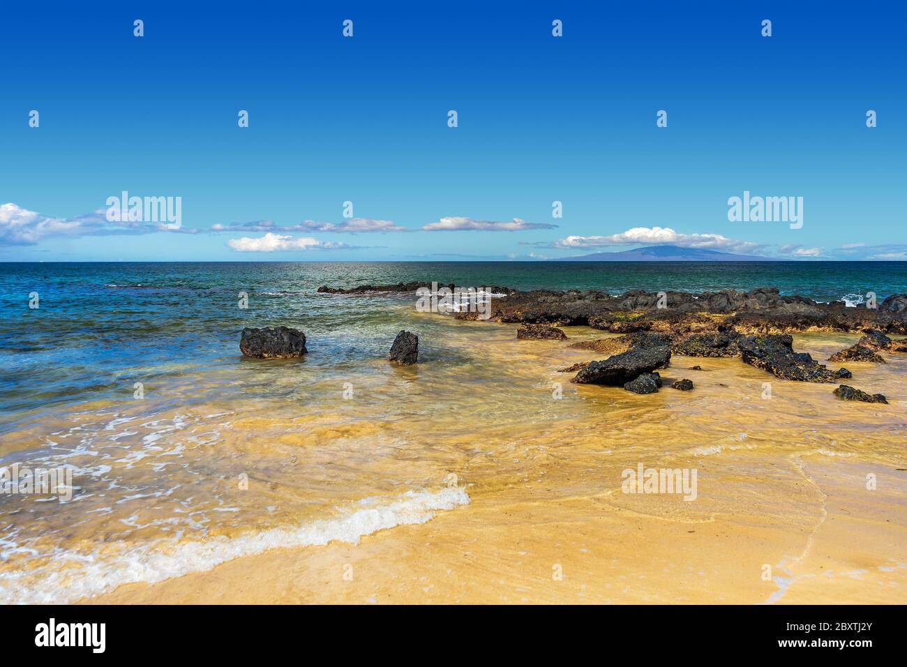 Ocean view with large black rocks from Kamaole Beach on the Hawaiian ...