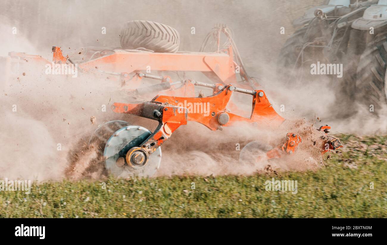 Agricultural equipment shreds the plowed land. A crawler tractor pulls ...
