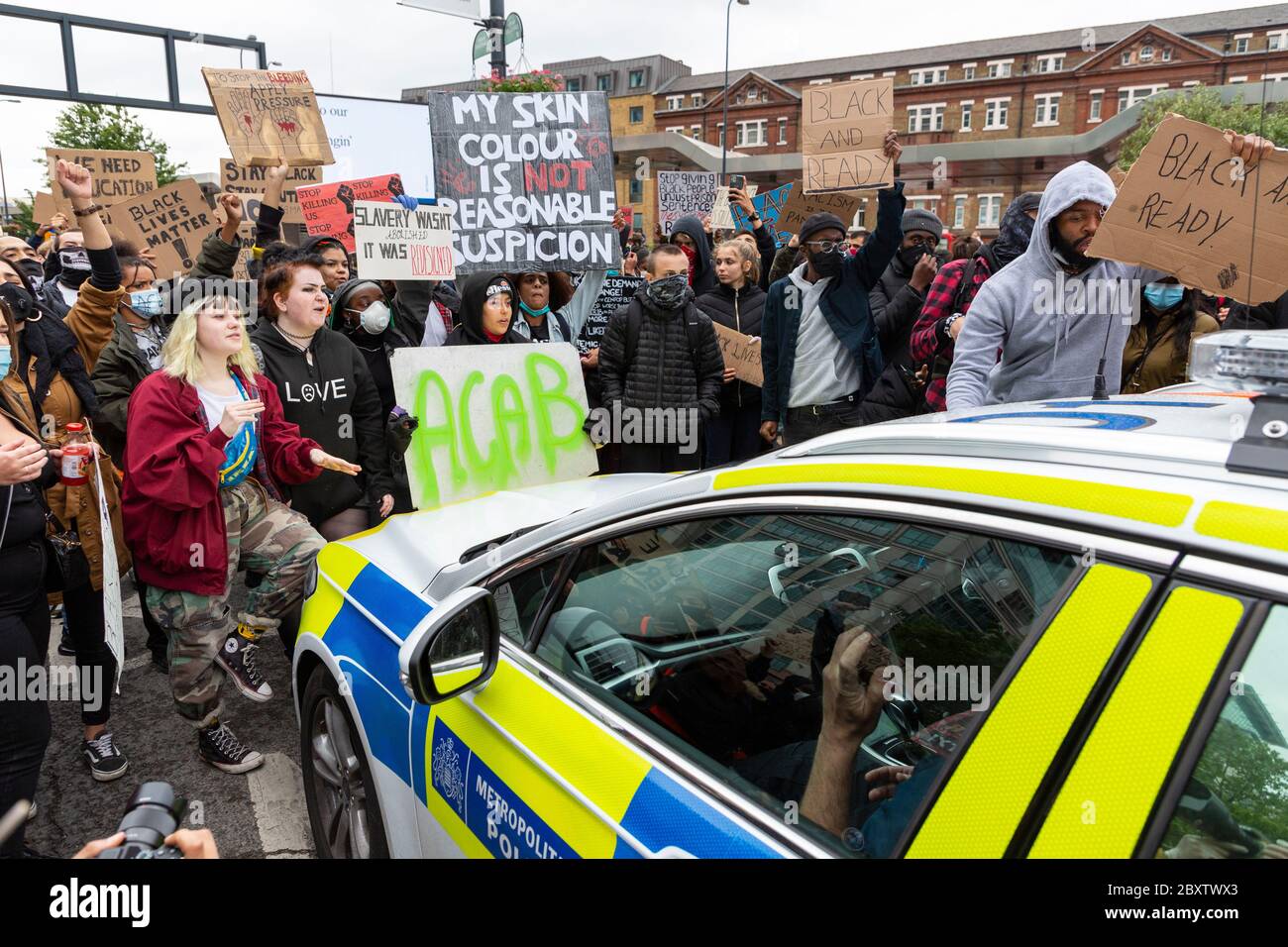 A crowd of protesters surround and obstruct a police car during the ...