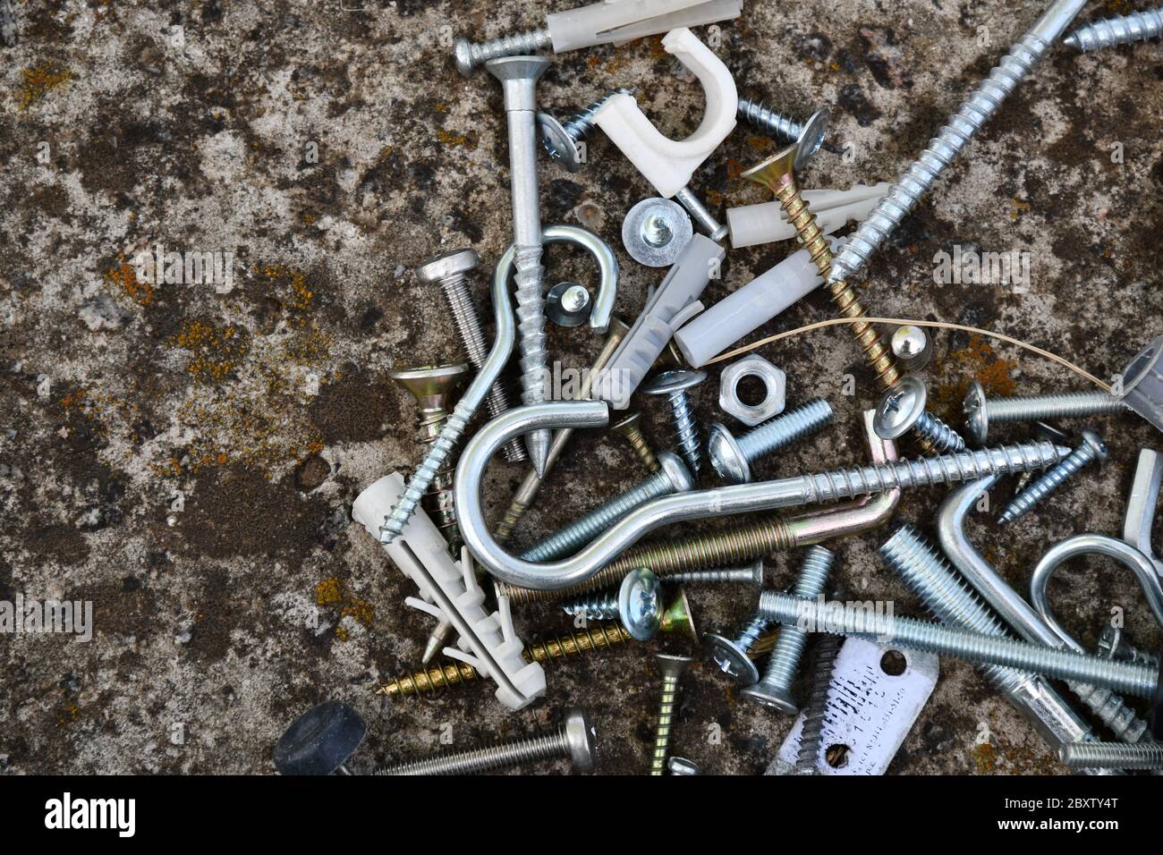 Metal bolts and nuts, hooks and dowels on grunge stone background with ...