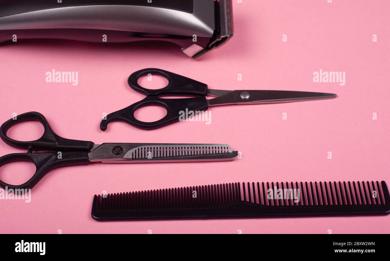 Hairdressing tools on a pink background, clipper, comb and scissors ...