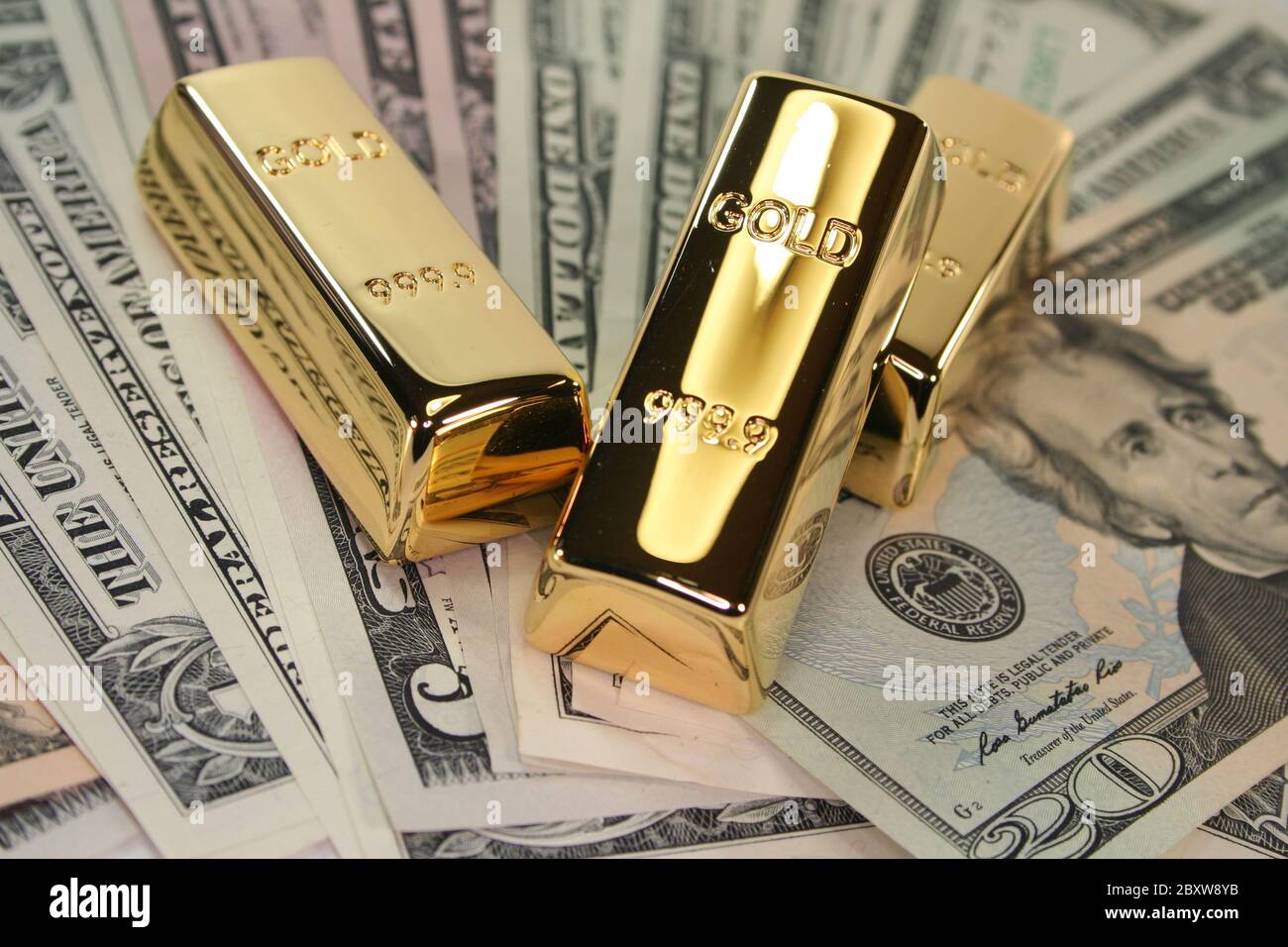 three gold bars on dollar bills Stock Photo - Alamy